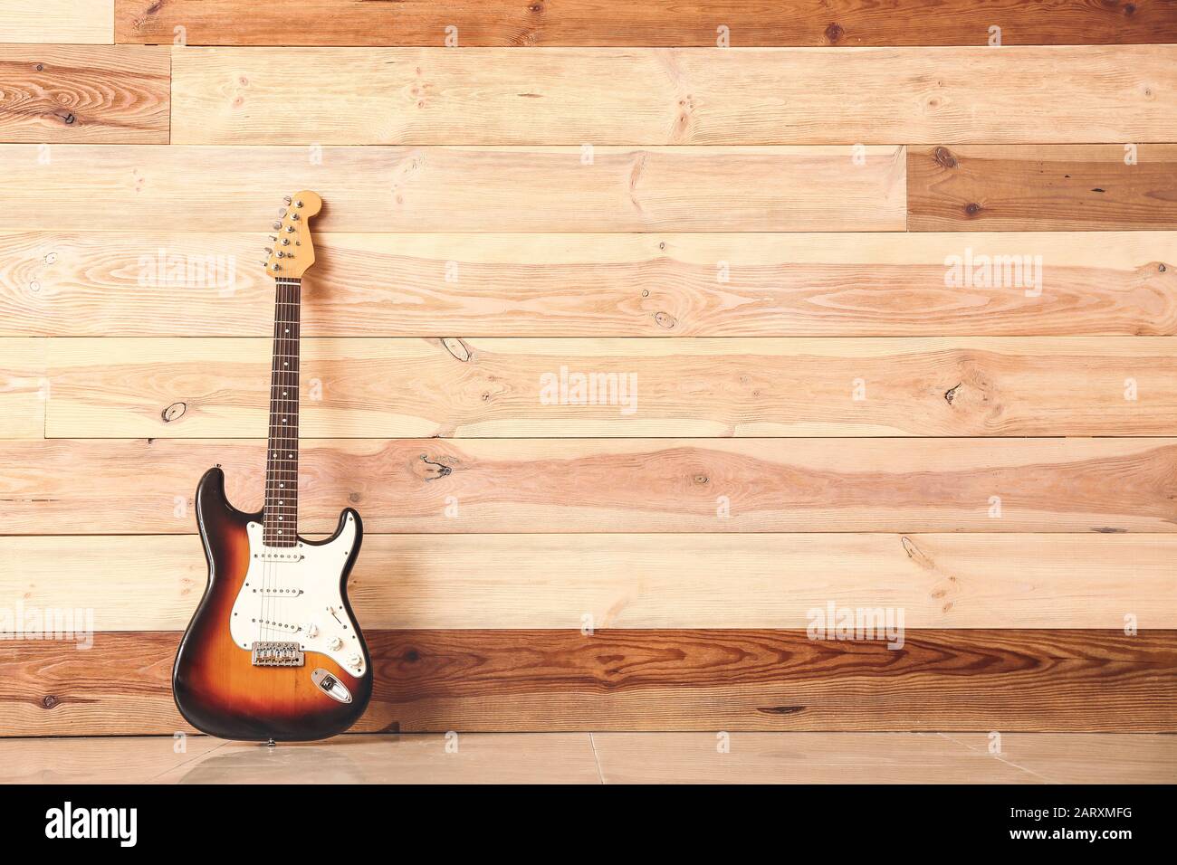 Modern bass guitar near wooden wall Stock Photo - Alamy