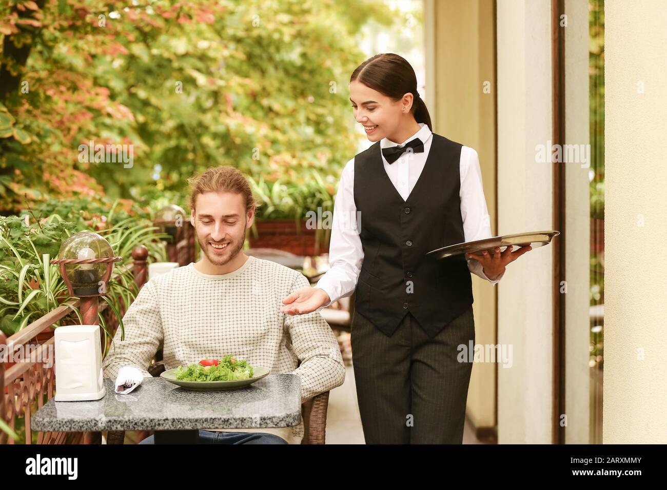 Waitress serving client in restaurant Stock Photo - Alamy