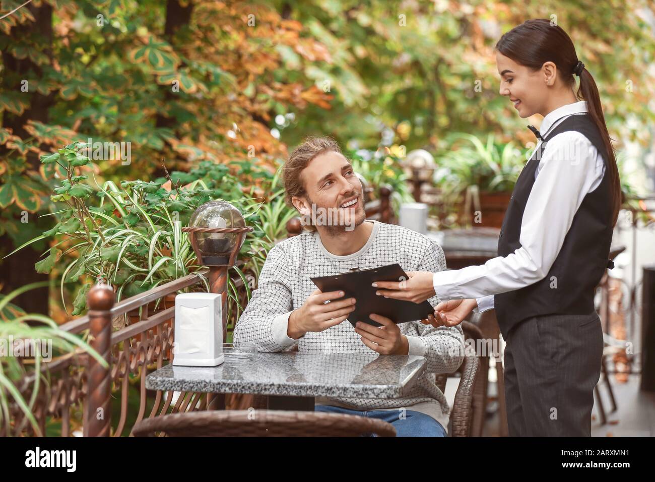 Waitress serving client in restaurant Stock Photo - Alamy