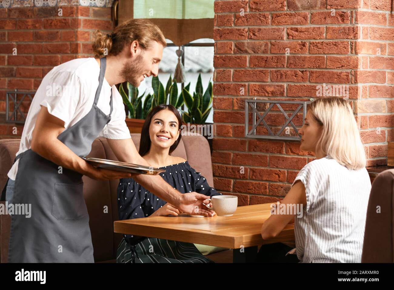 Waiter serving clients in restaurant Stock Photo - Alamy