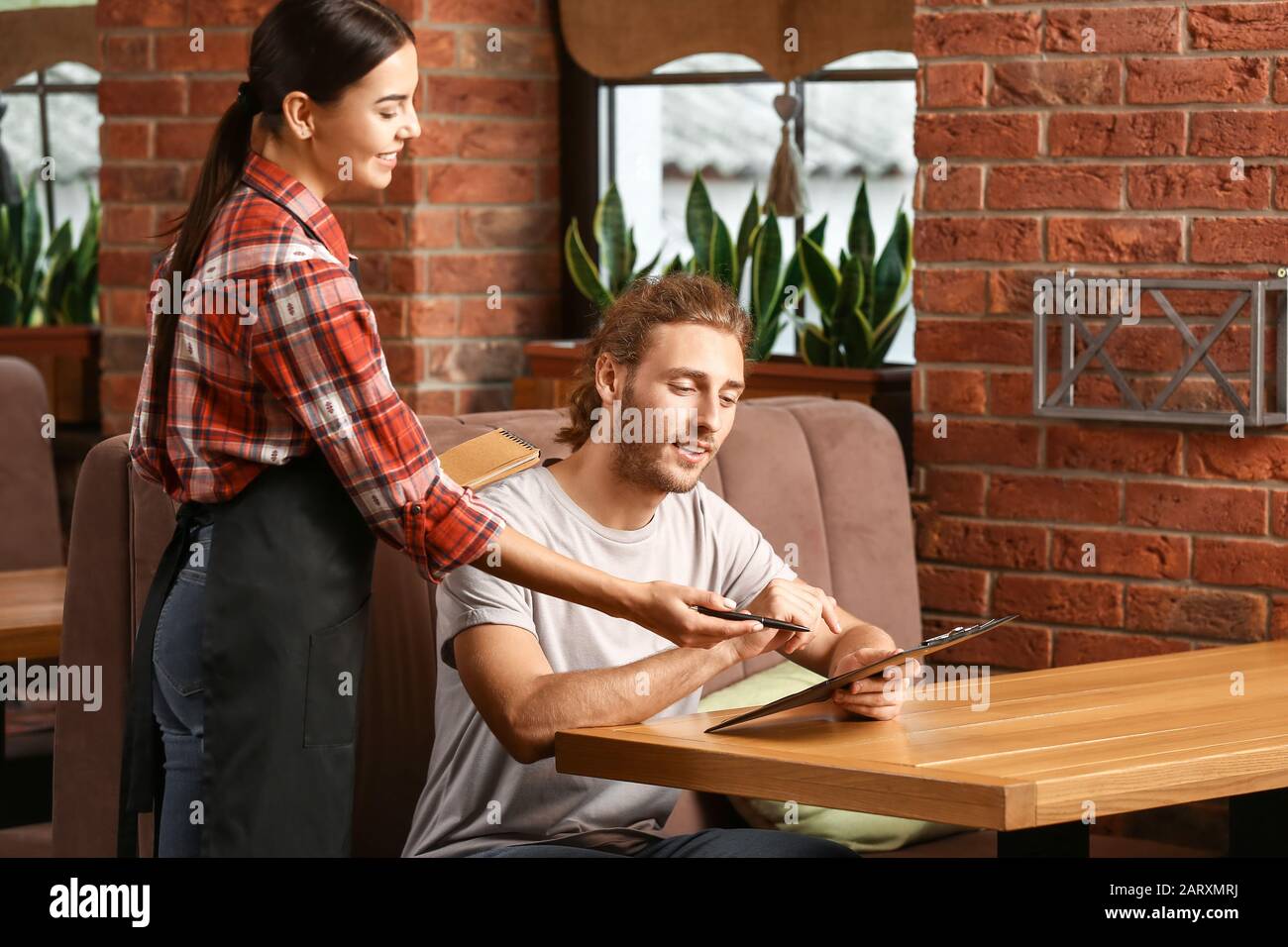 Waitress serving client in restaurant Stock Photo - Alamy