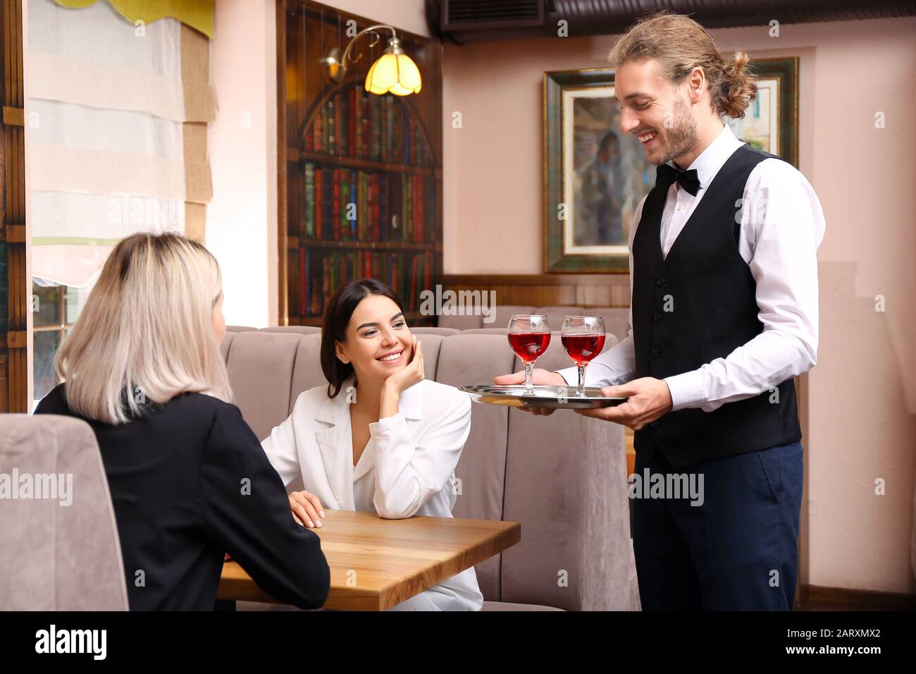 Waiter serving clients in restaurant Stock Photo - Alamy