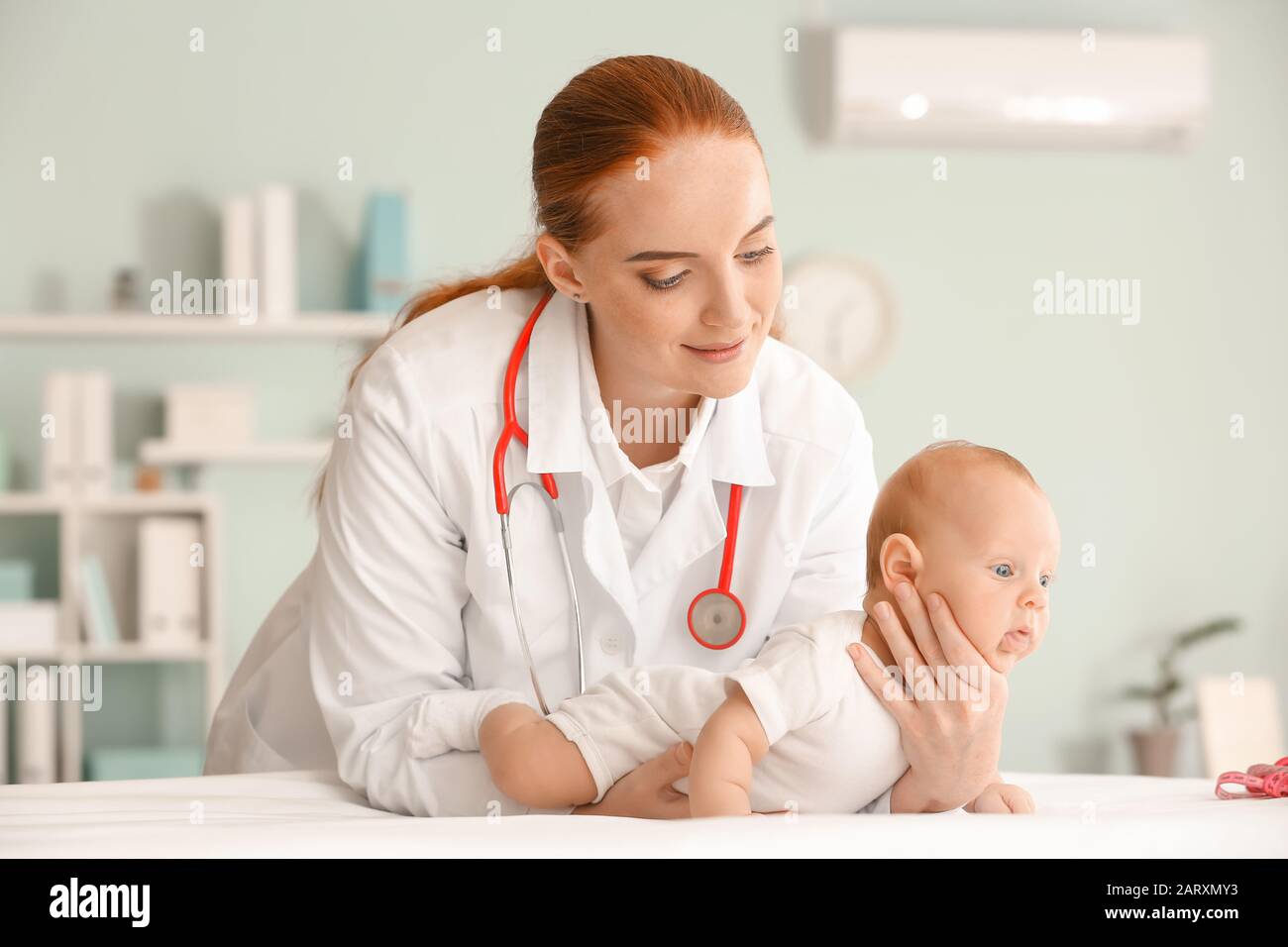 Pediatrician examining cute baby in clinic Stock Photo - Alamy