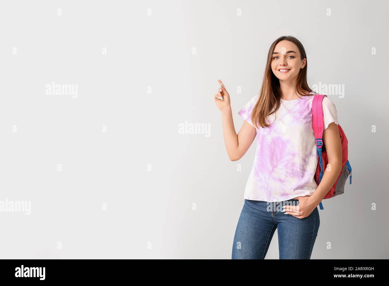 Beautiful female student pointing at something on white background ...