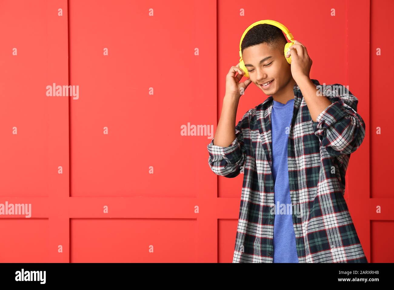 African-American teenage boy listening to music on color background ...