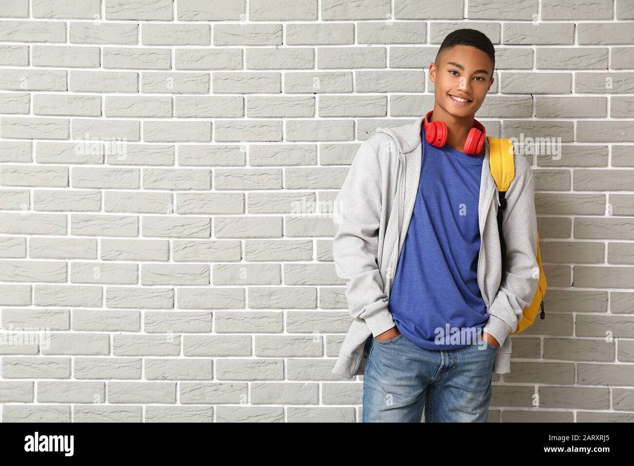 Portrait of African-American teenage schoolboy on brick background ...