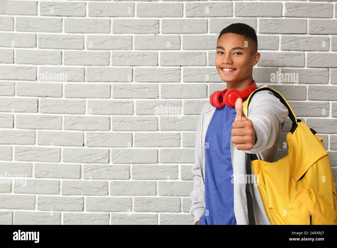 Portrait of African-American teenage schoolboy showing thumb-up on ...
