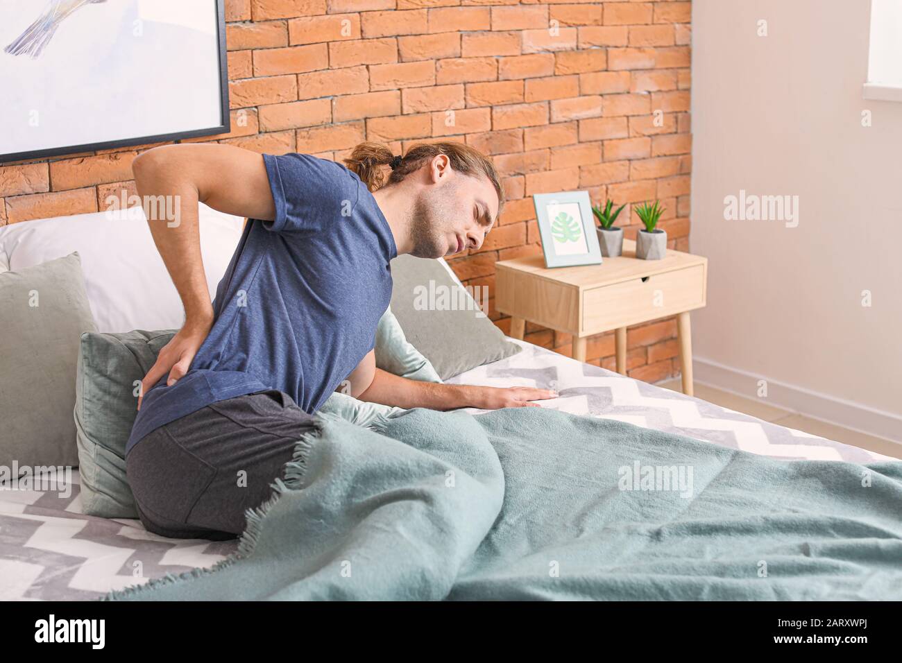 Young man suffering from back pain at home Stock Photo - Alamy