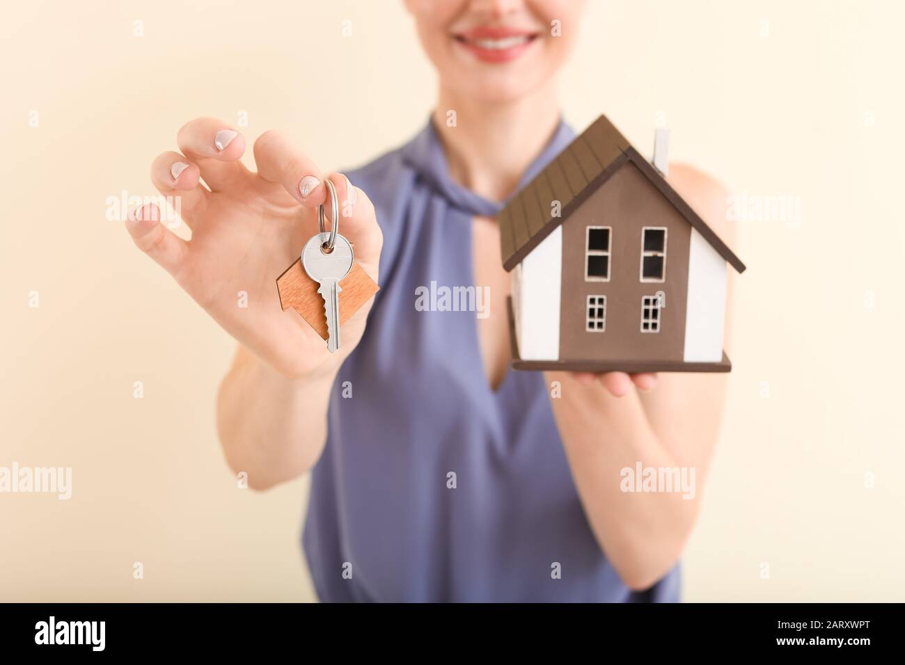 Female real estate agent with key and model of house on light ...