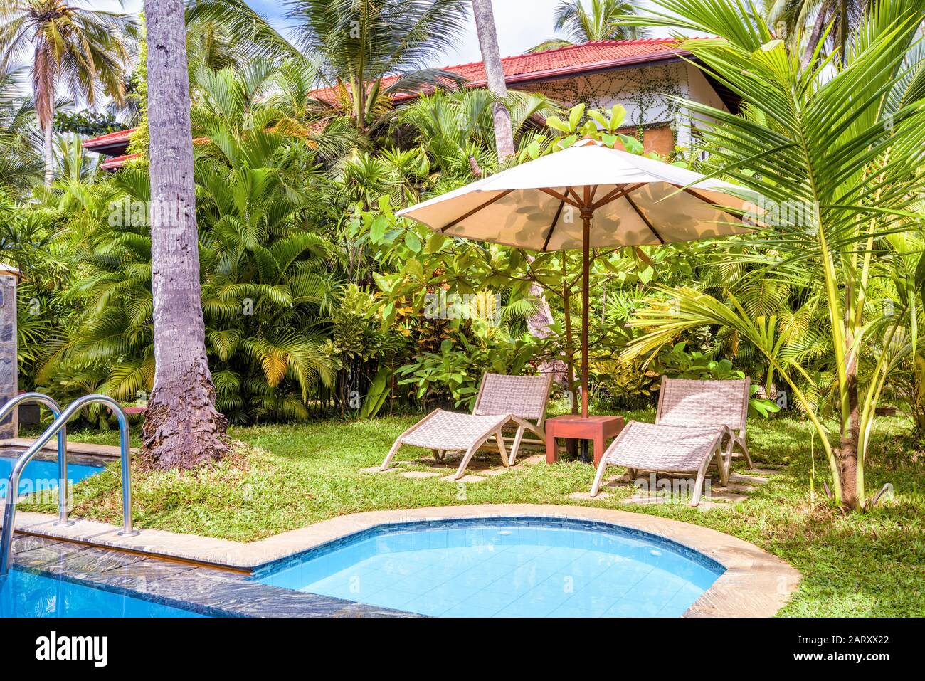 Pool with umbrella and beach beds in tropical hotel or residential ...