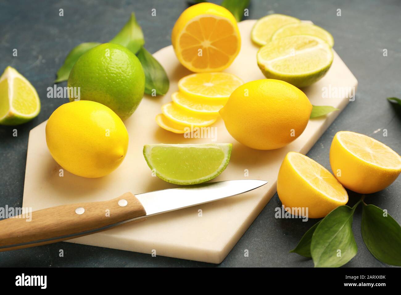 Cutting board with ripe lemons and limes on dark background Stock Photo ...