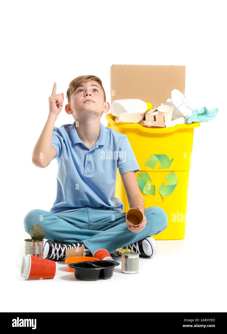 Little boy pointing at something while sitting near container with ...