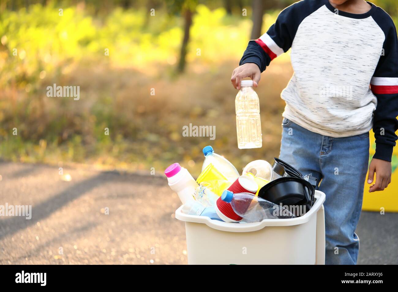 Little African-American boy collecting trash outdoors. Concept of ...