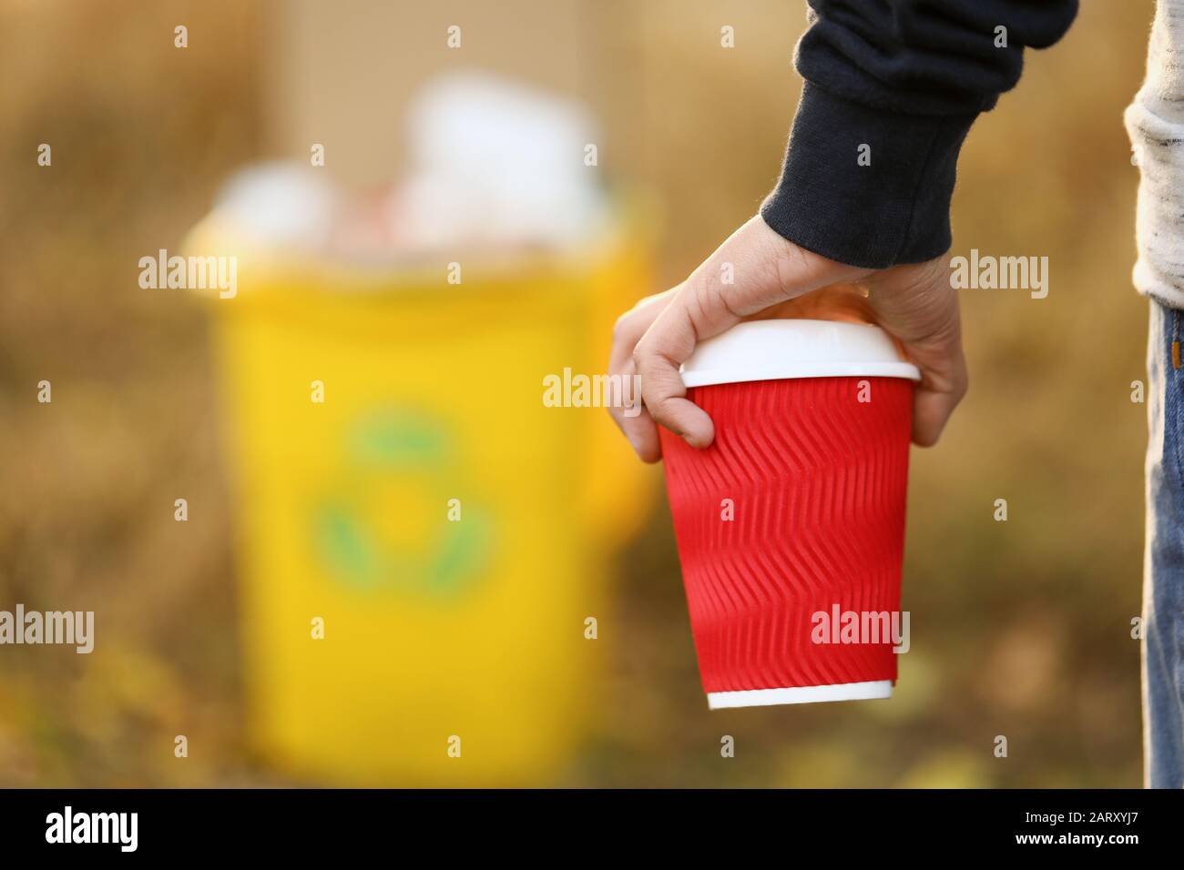 Little boy throwing out paper cup in trash container outdoors, closeup ...