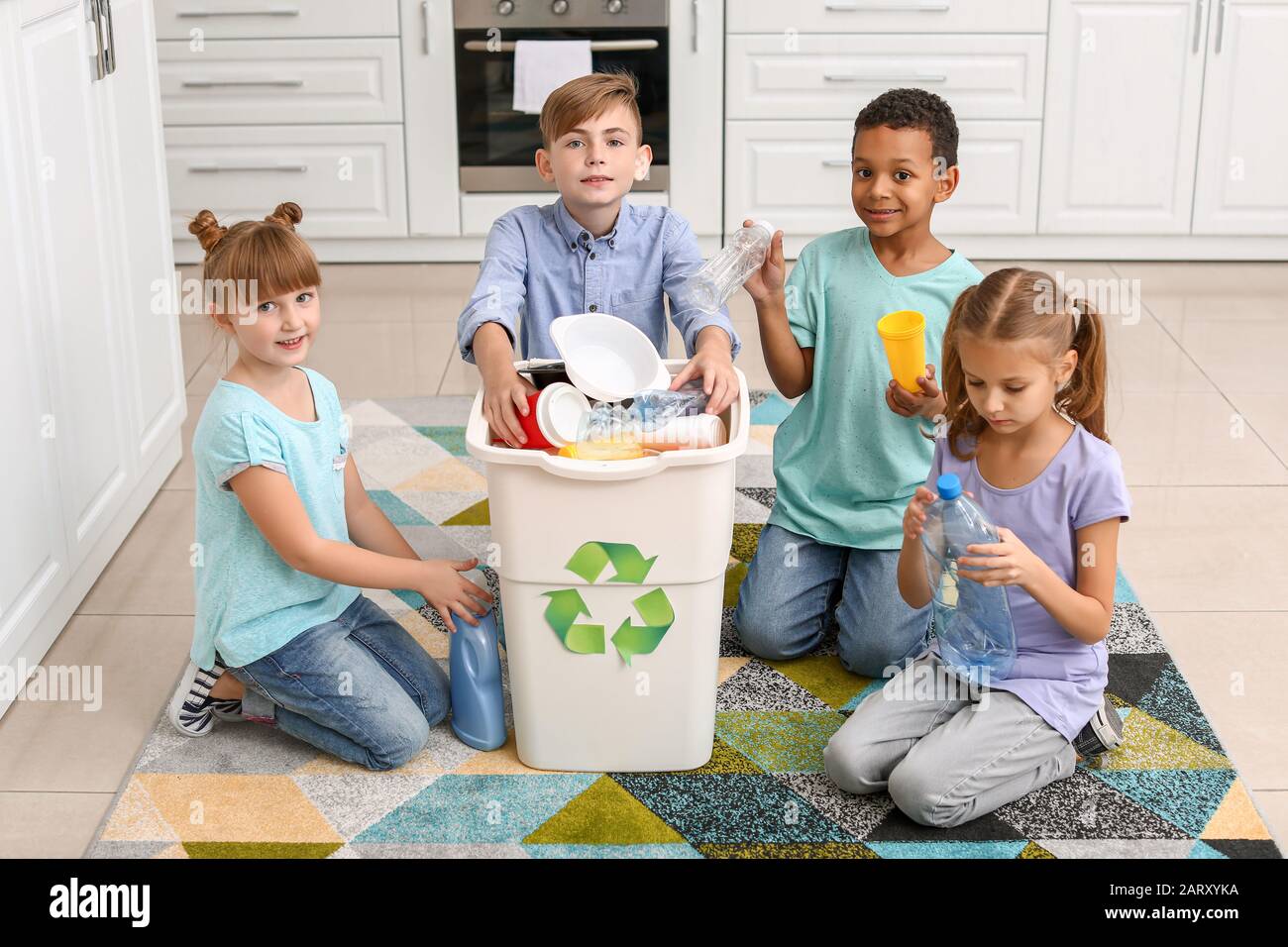 Little children and container with trash in kitchen. Concept of ...
