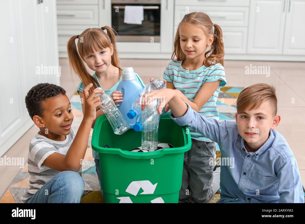 Little children and container with trash in kitchen. Concept of ...