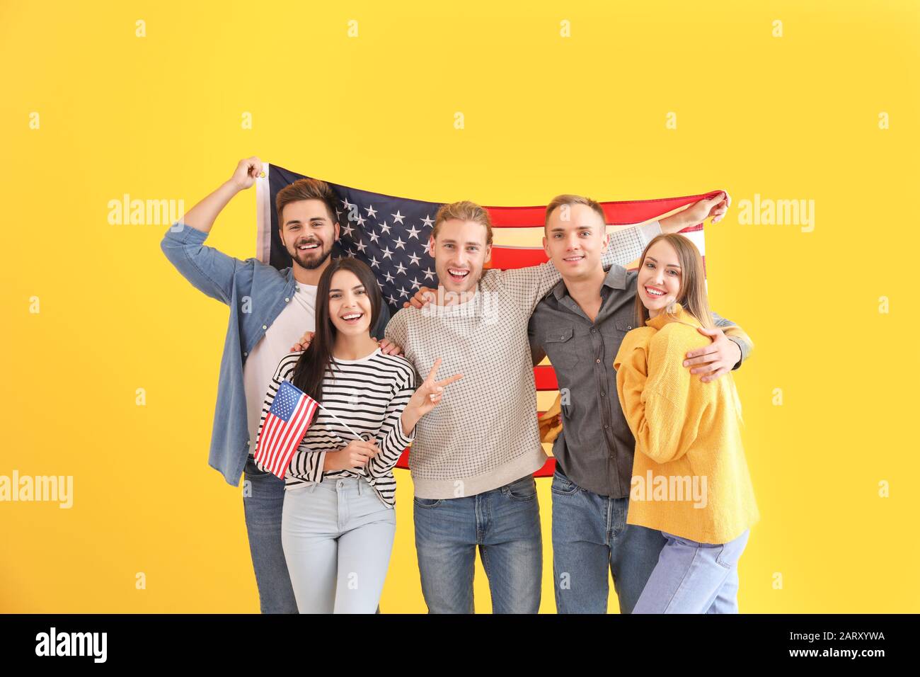 Happy young friends with national flags of USA on color background ...