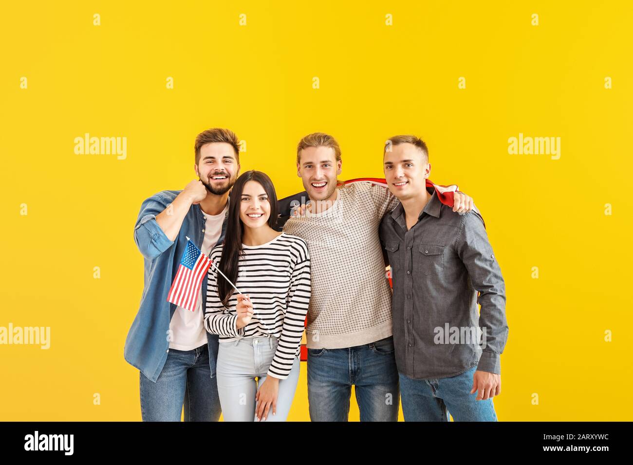 Happy young friends with national flags of USA on color background ...
