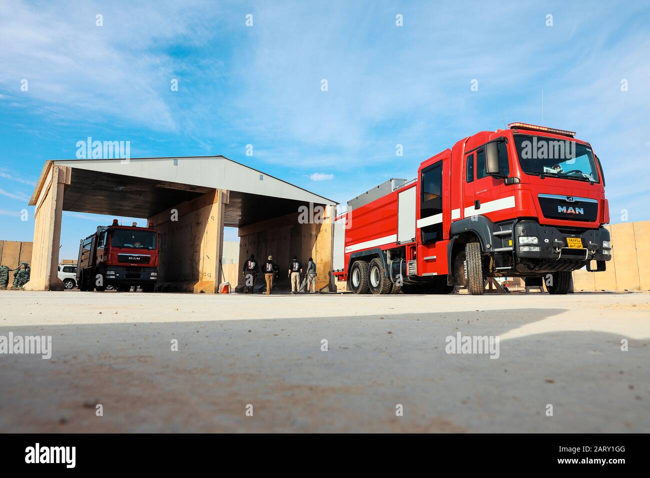 Civilian contractors clean debris off of fire trucks at Al Asad Air ...