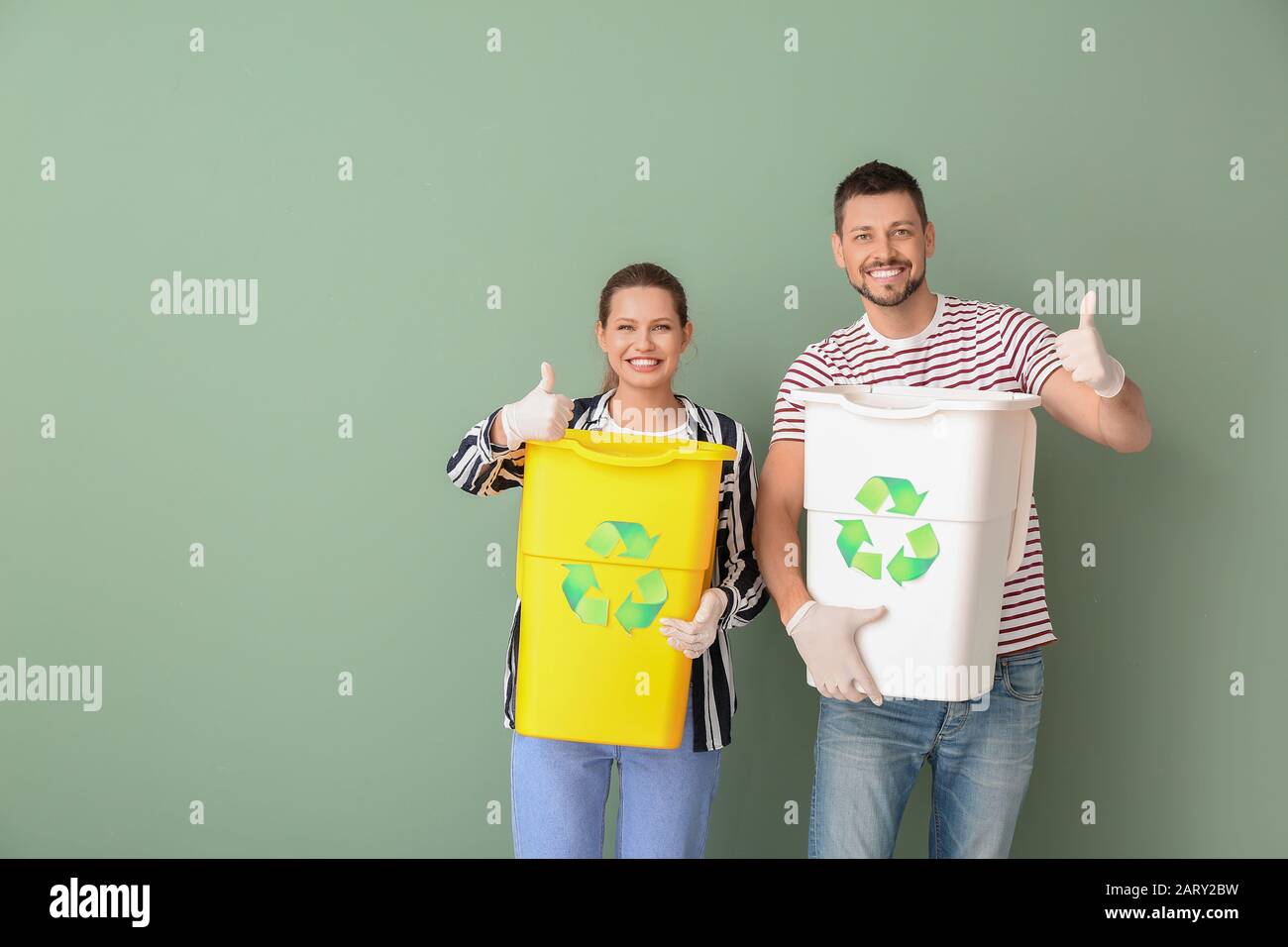 Couple with containers for garbage showing thumb-up on color background ...
