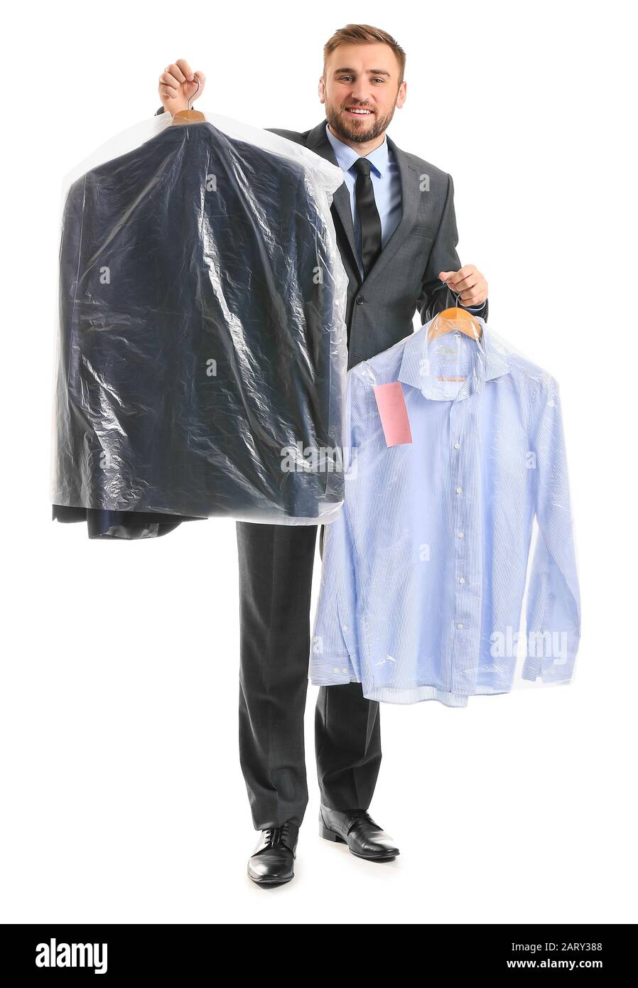 Male worker of modern dry-cleaner's with clothes on white background ...
