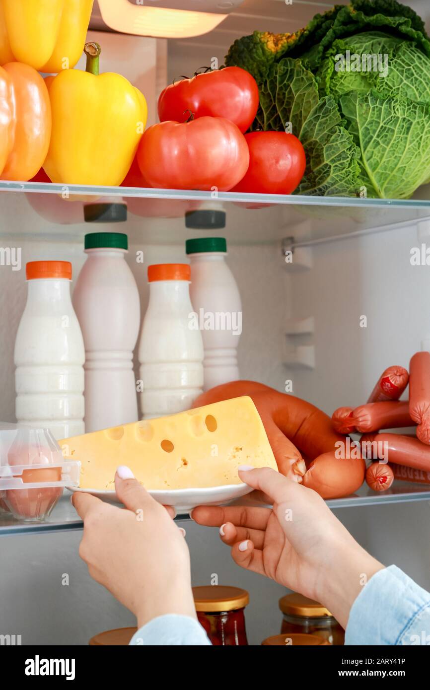 Woman taking food out of fridge Stock Photo - Alamy