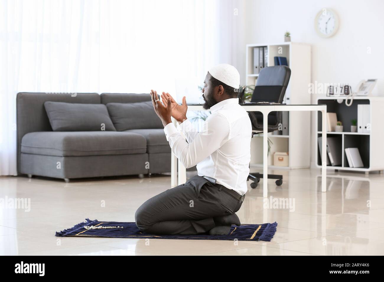 African-American Muslim man praying in office Stock Photo - Alamy