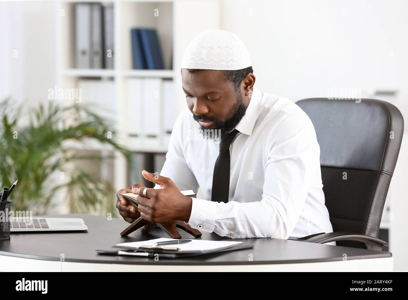 African-American Muslim man praying in office Stock Photo - Alamy