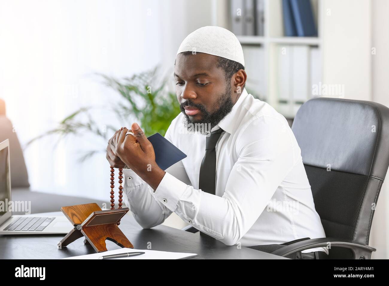 African-American Muslim man praying in office Stock Photo - Alamy