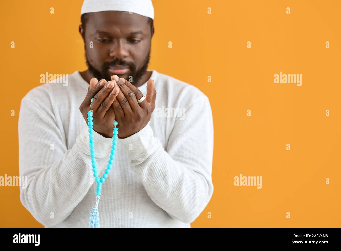 African-American Muslim man praying against color background Stock ...