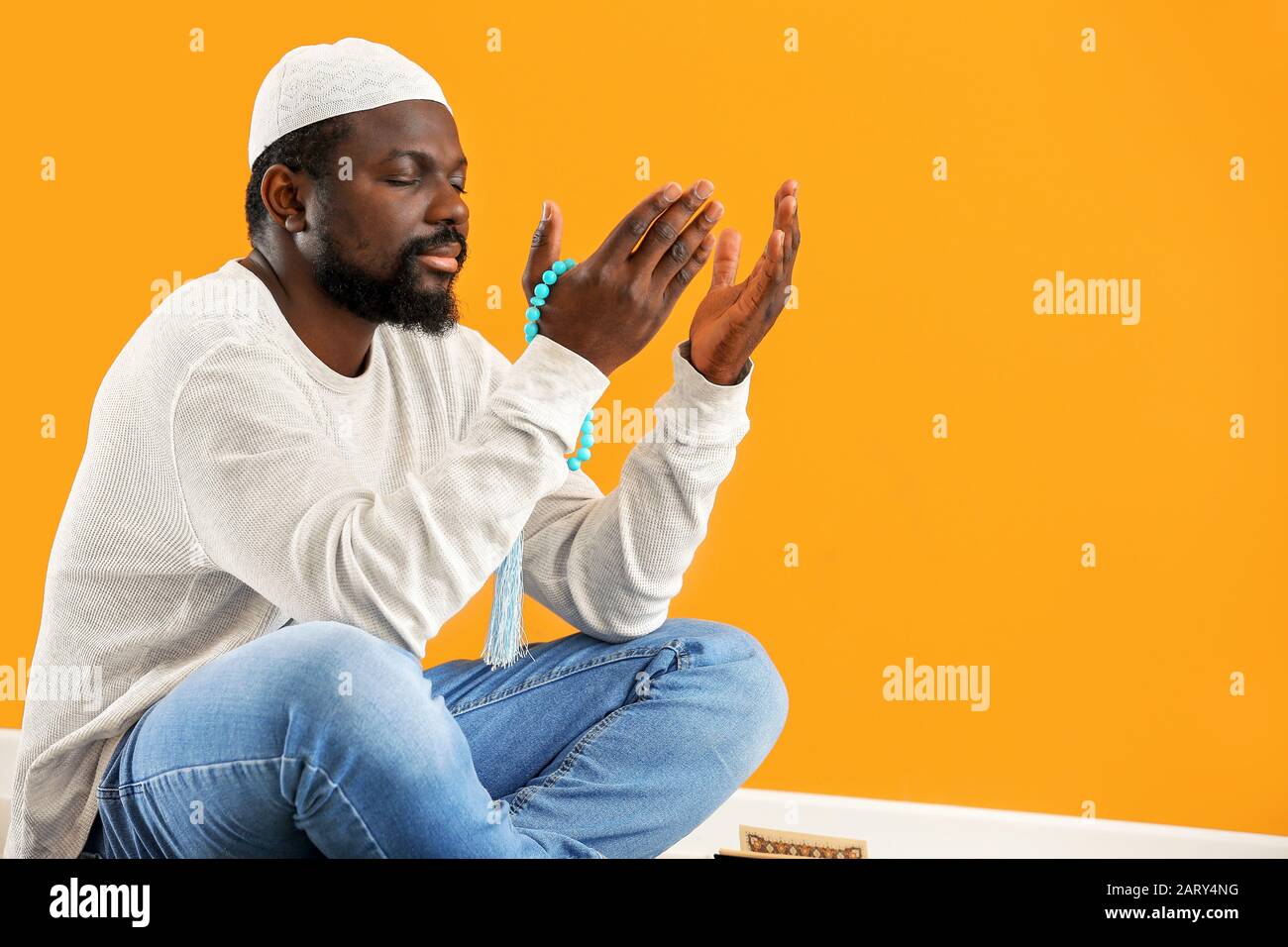 African-American Muslim man praying against color background Stock ...