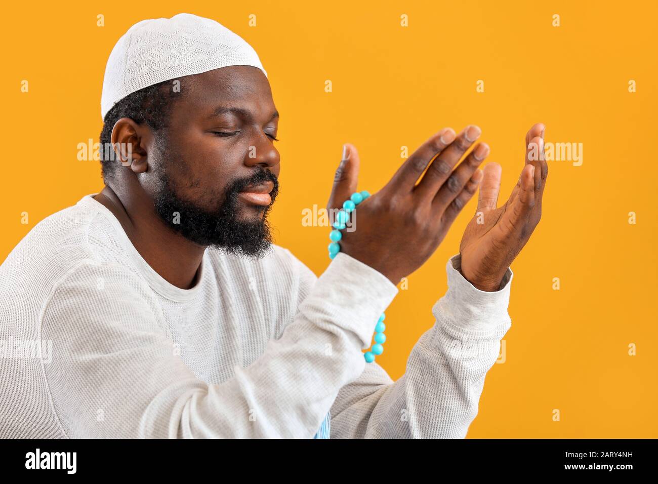 African-American Muslim man praying against color background Stock ...