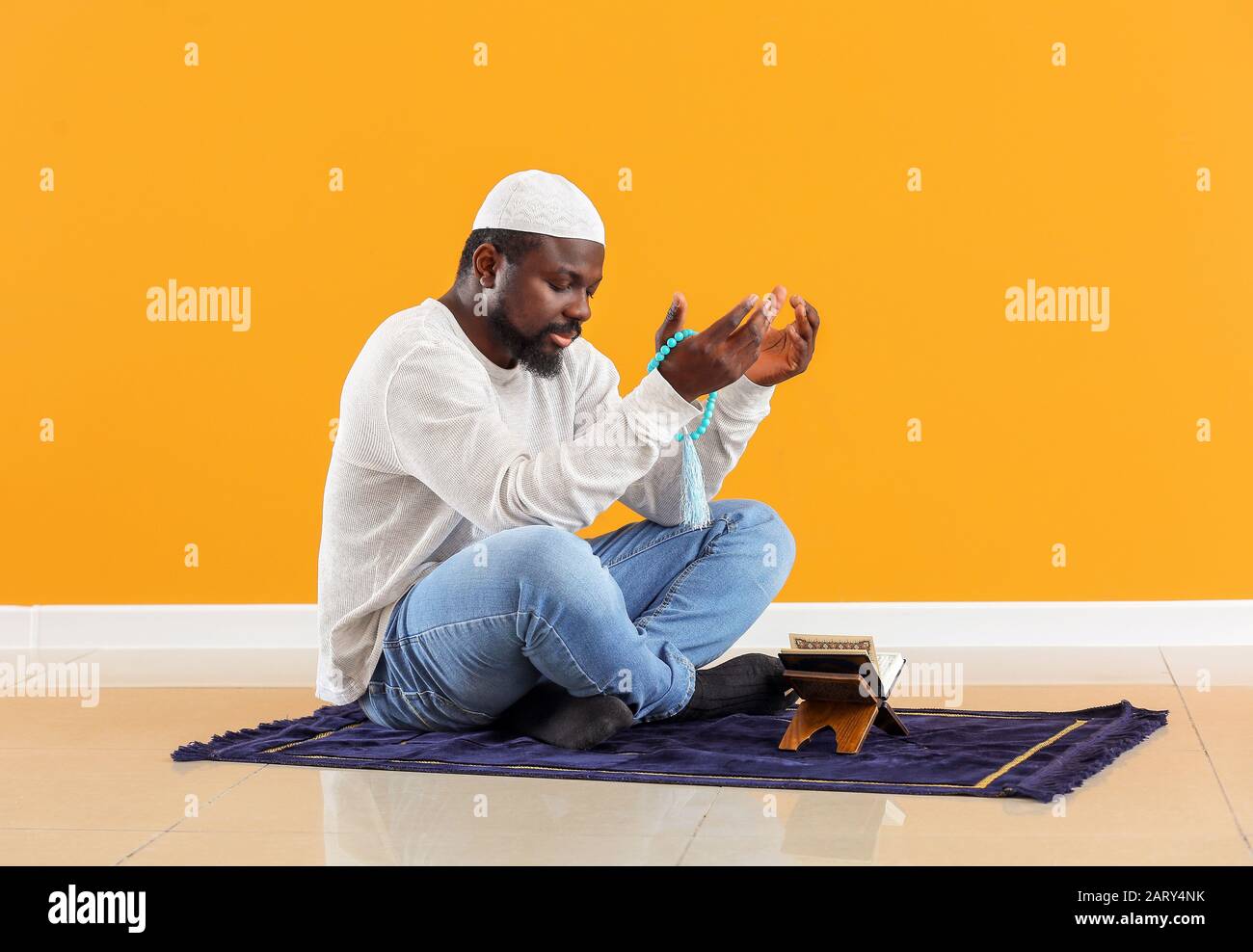 African-American Muslim man praying against color background Stock ...