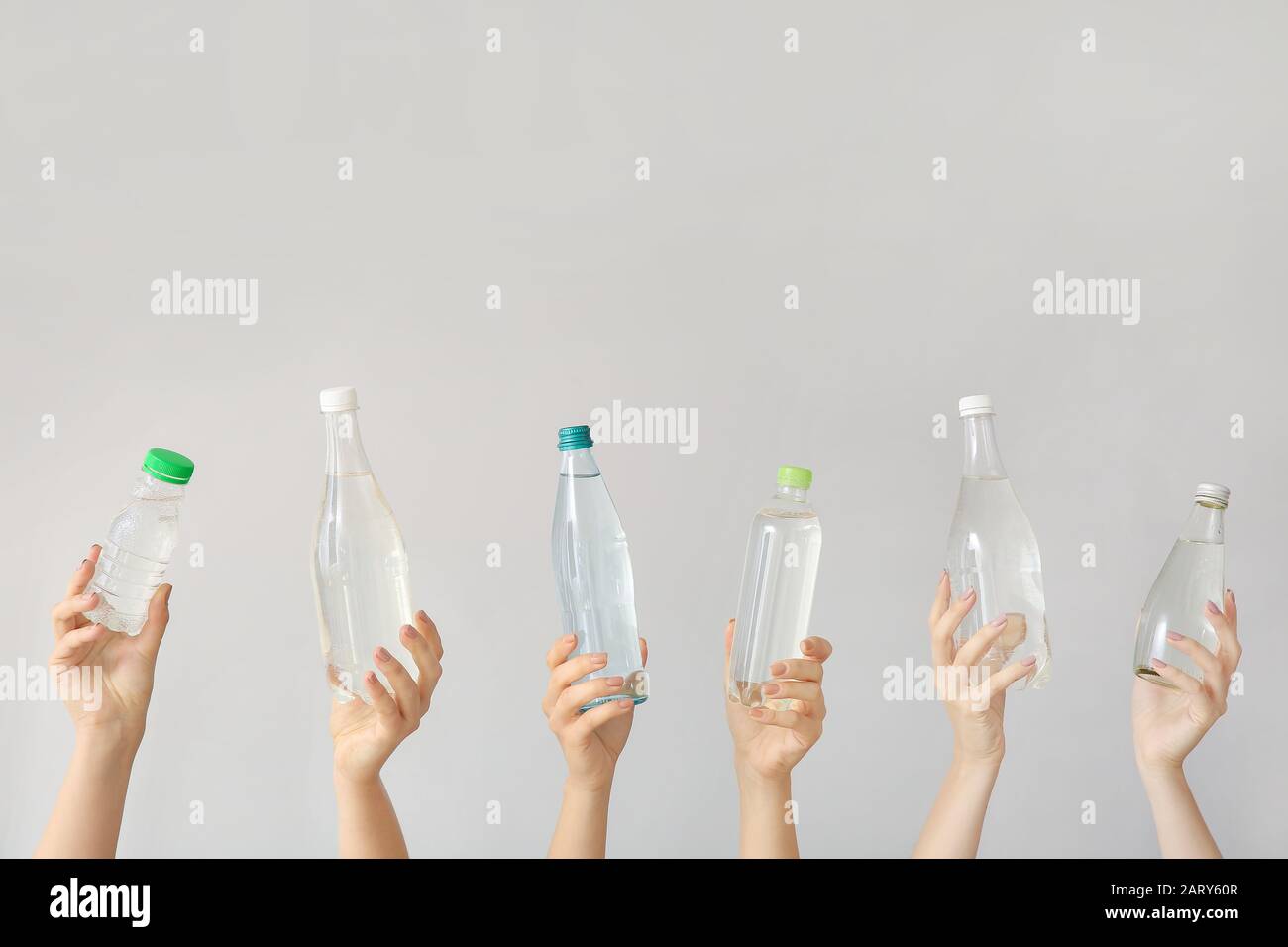Female hands with bottles of water on grey background Stock Photo - Alamy