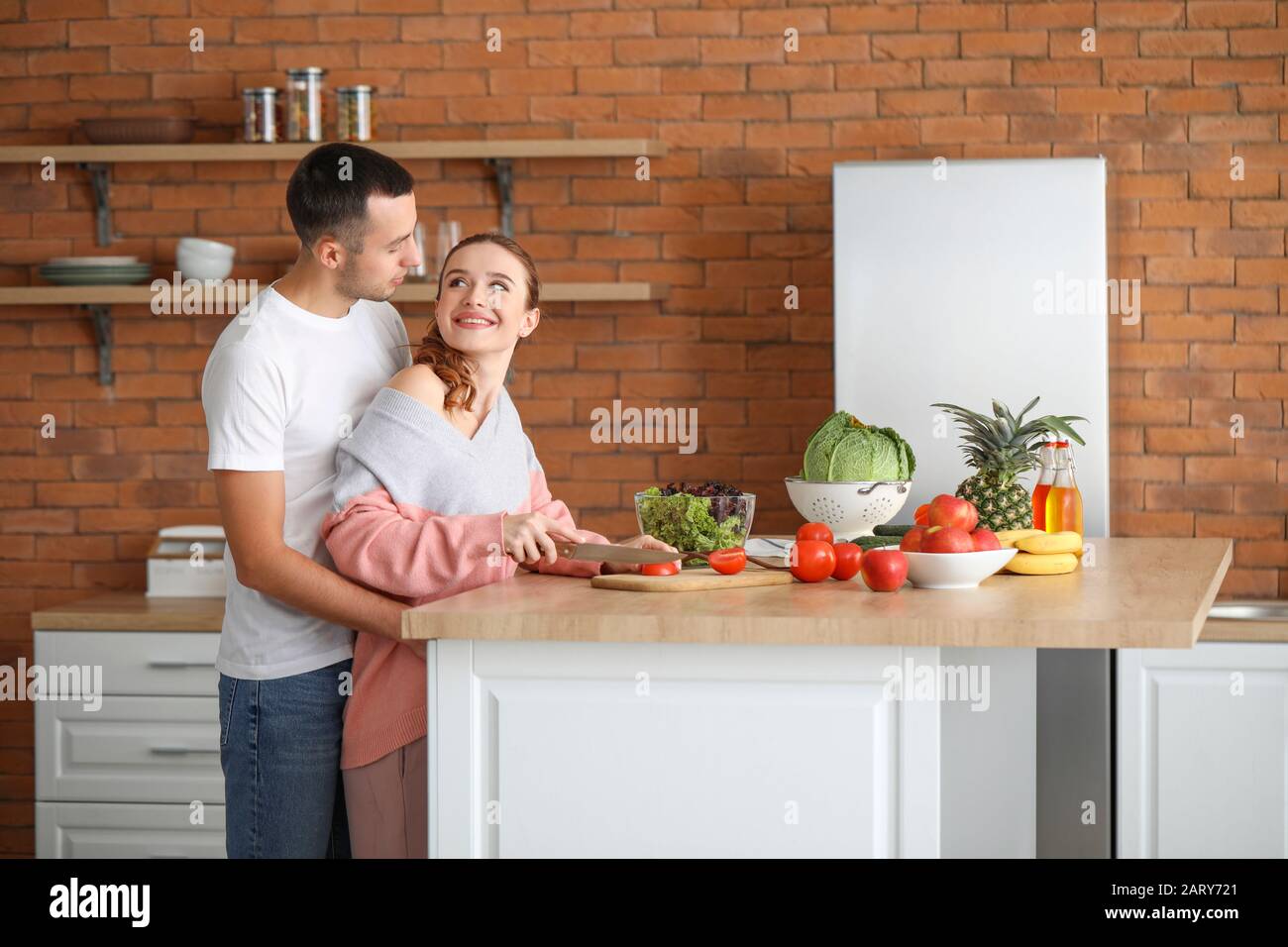 Beautiful young couple cooking together in kitchen Stock Photo - Alamy