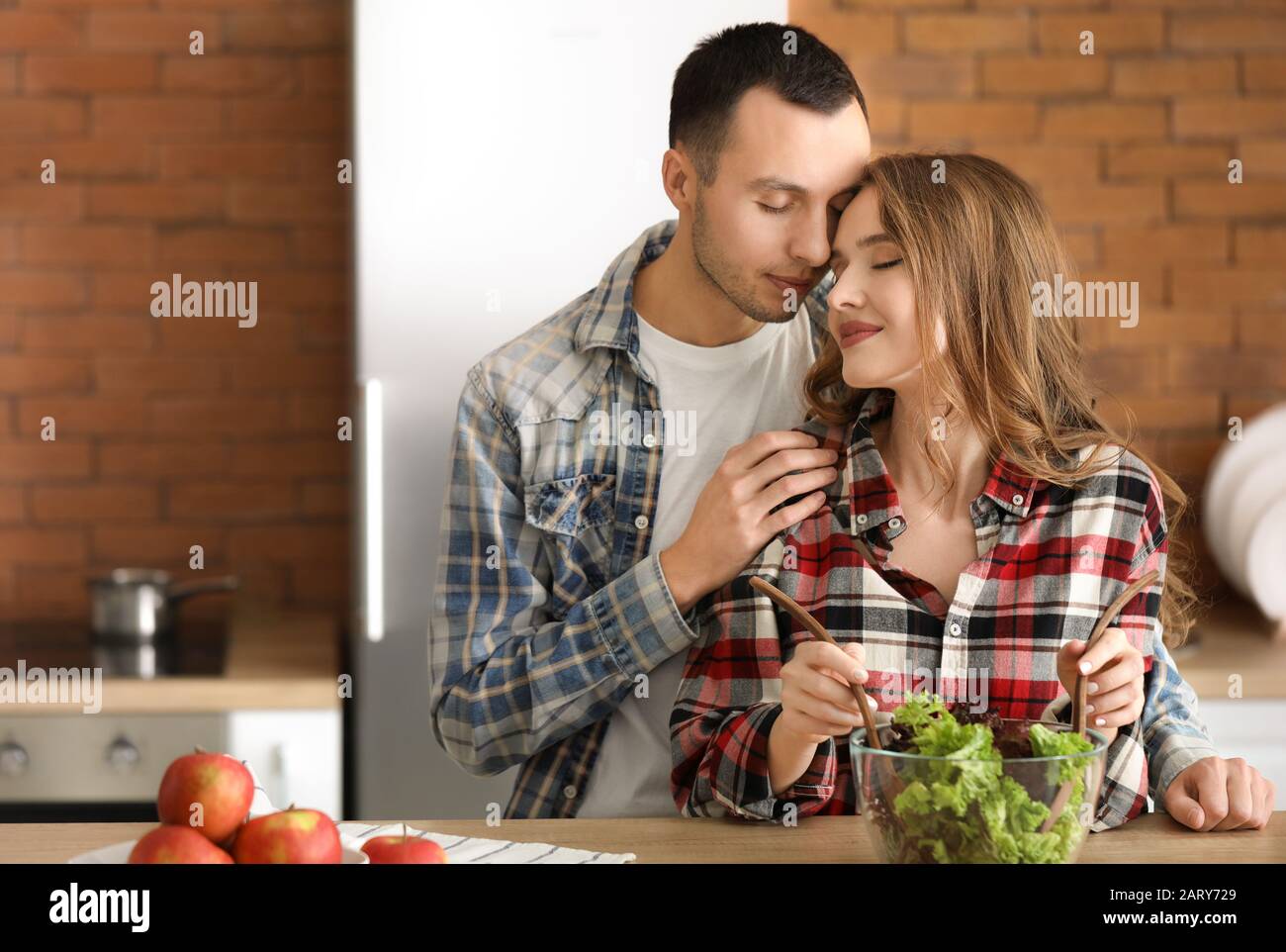 Beautiful young couple cooking together in kitchen Stock Photo - Alamy
