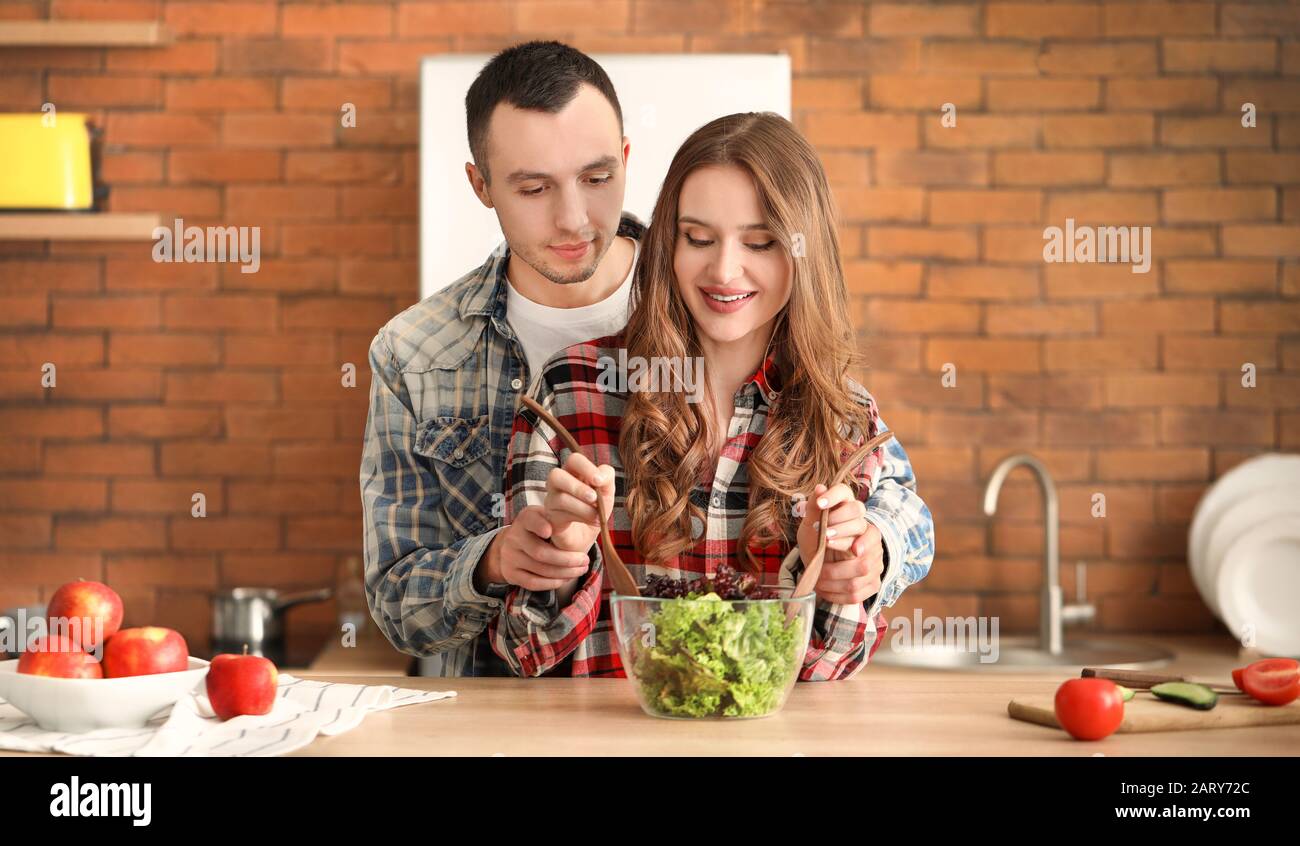 Beautiful young couple cooking together in kitchen Stock Photo - Alamy