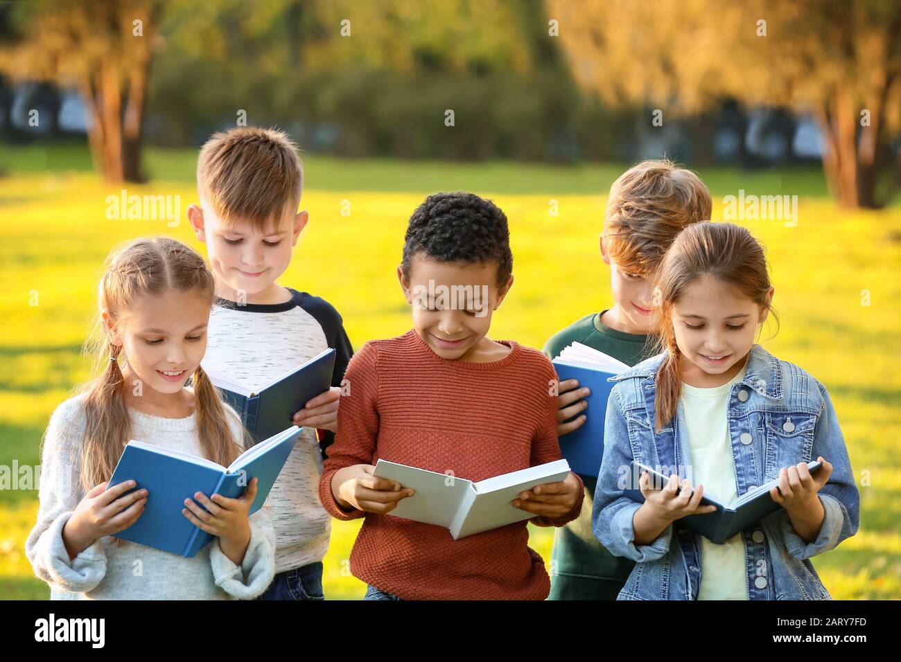 Cute little children reading books in park Stock Photo - Alamy