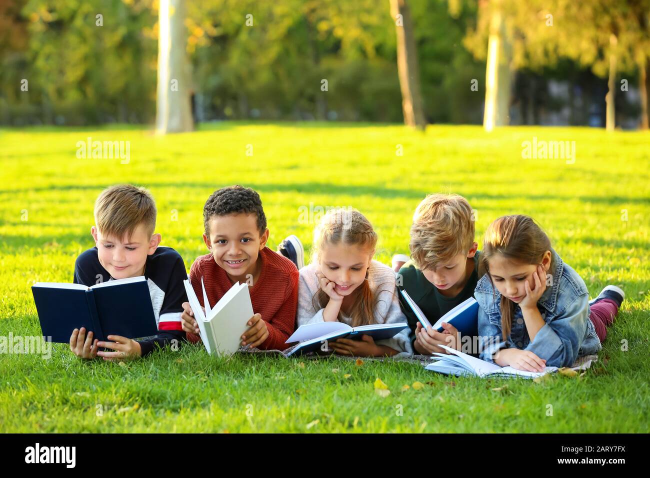 Cute little children reading books in park Stock Photo - Alamy