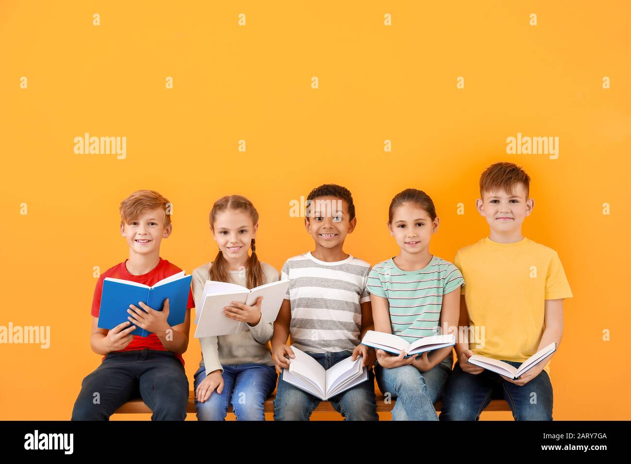 Cute little children reading books on color background Stock Photo - Alamy
