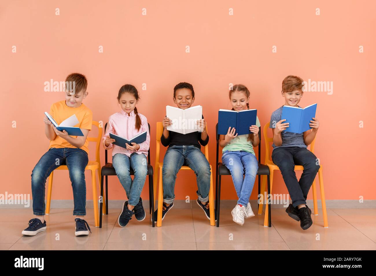 Cute little children reading books on color background Stock Photo - Alamy