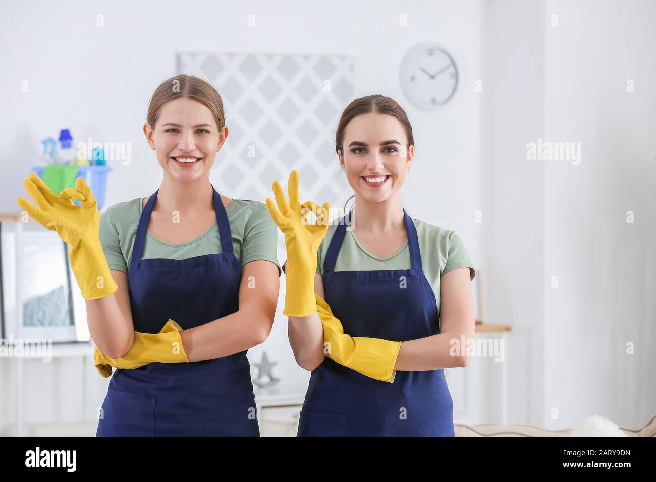 Female janitors showing OK gesture in room Stock Photo - Alamy