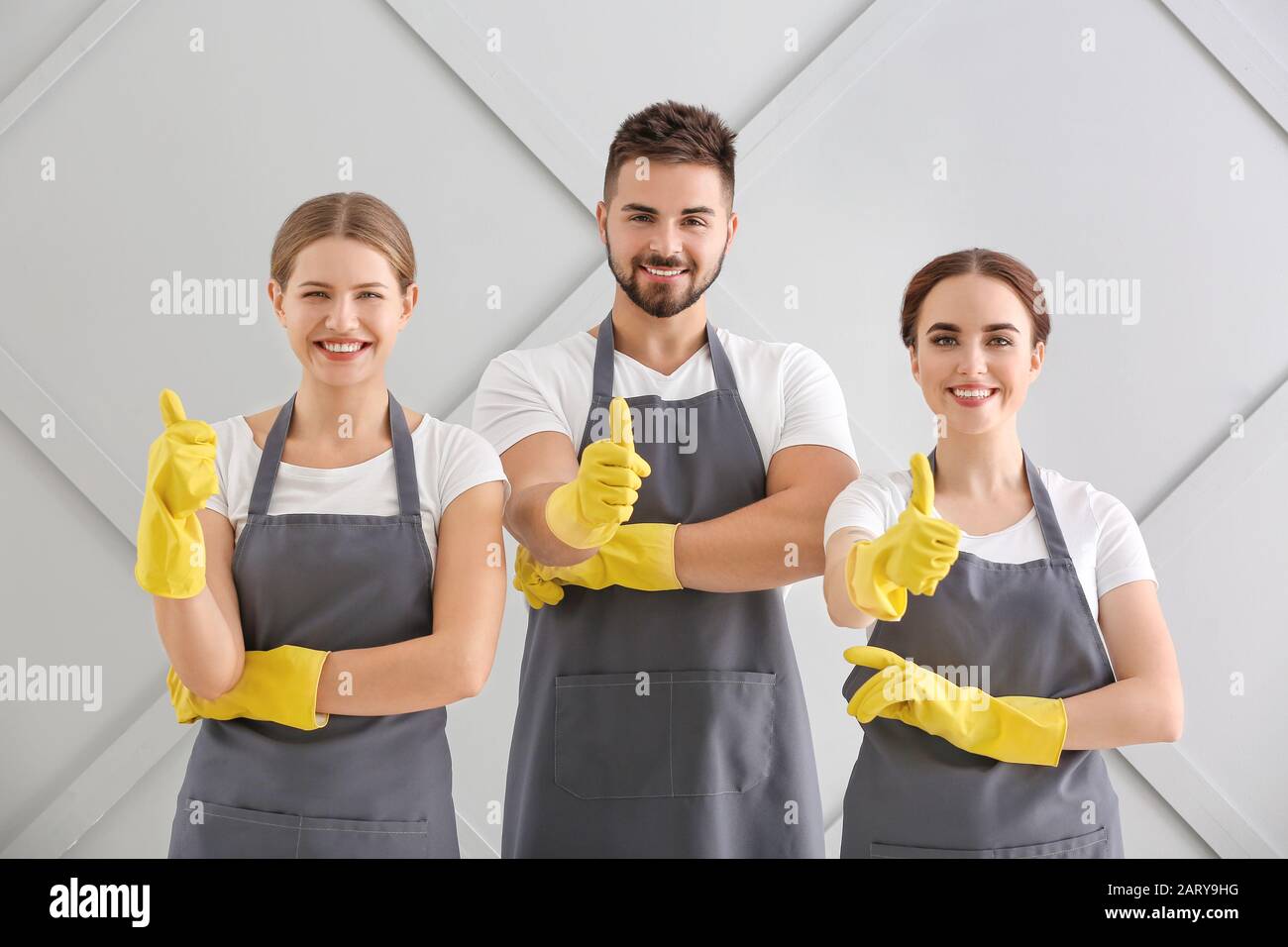 Team of janitors showing thumb-up gesture on grey background Stock ...