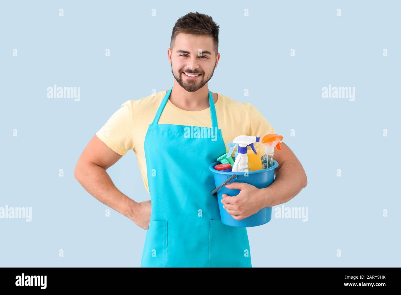 Male janitor with cleaning supplies on color background Stock Photo - Alamy