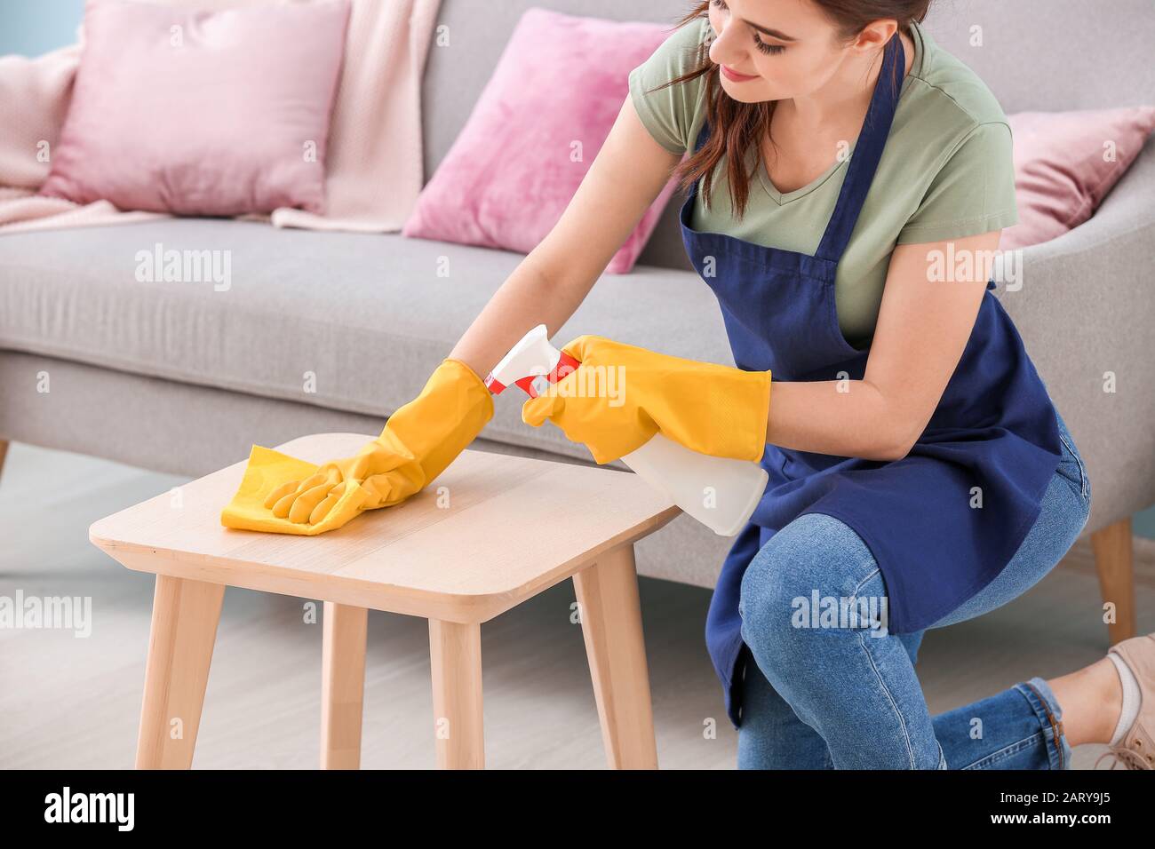 Female janitor cleaning table in room Stock Photo - Alamy