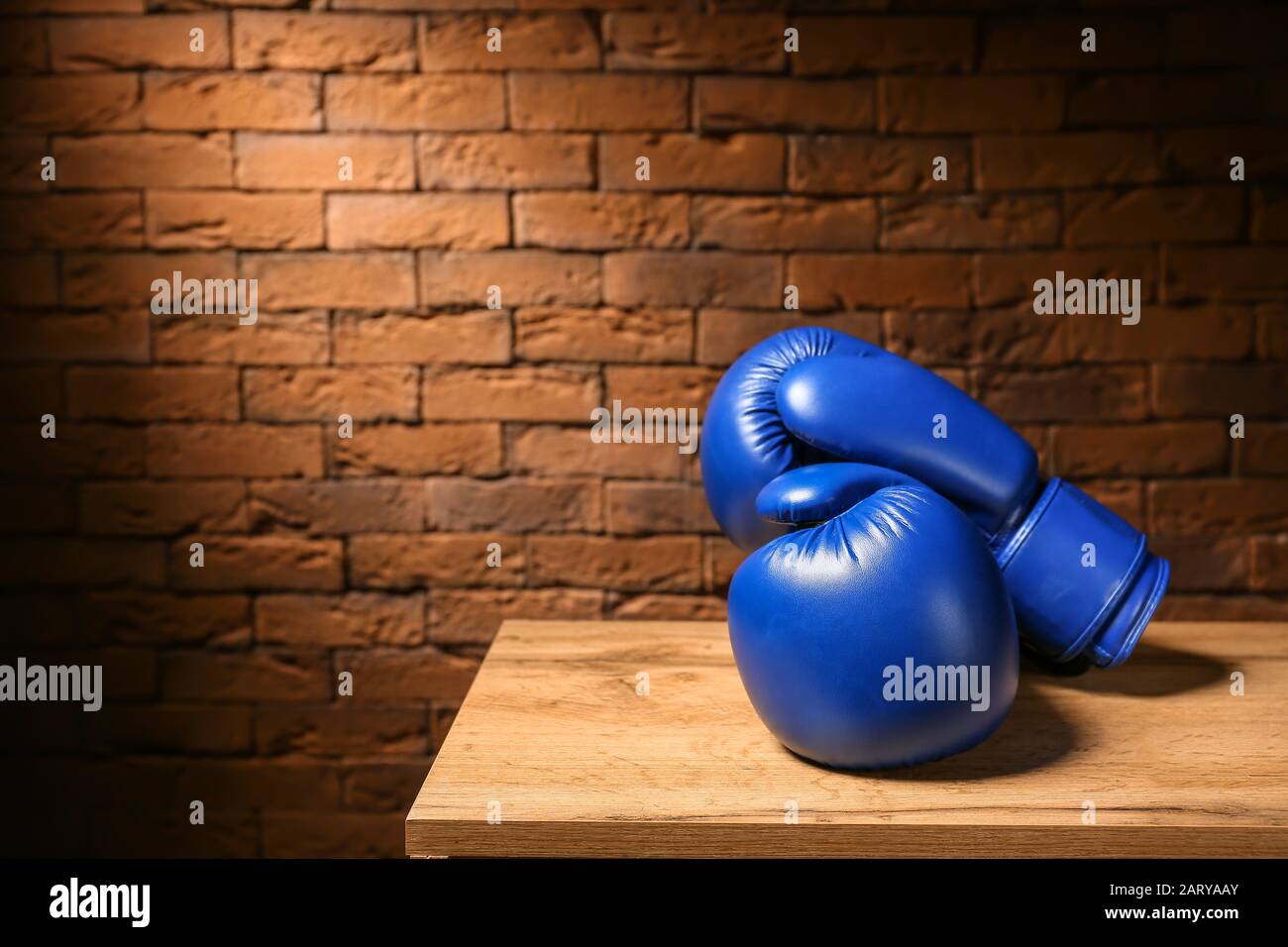 Pair of boxing gloves on table against brick wall Stock Photo - Alamy