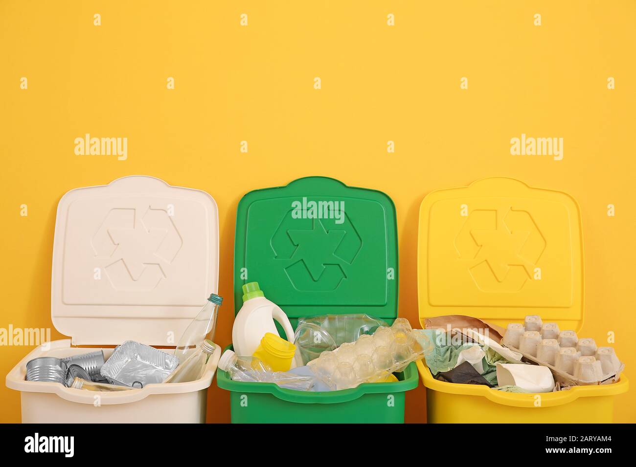 Containers with different types of garbage near color wall. Recycling ...
