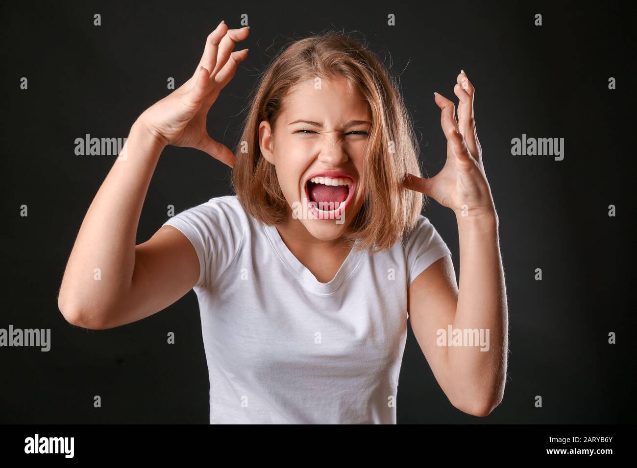 Screaming teenage girl on dark background Stock Photo - Alamy