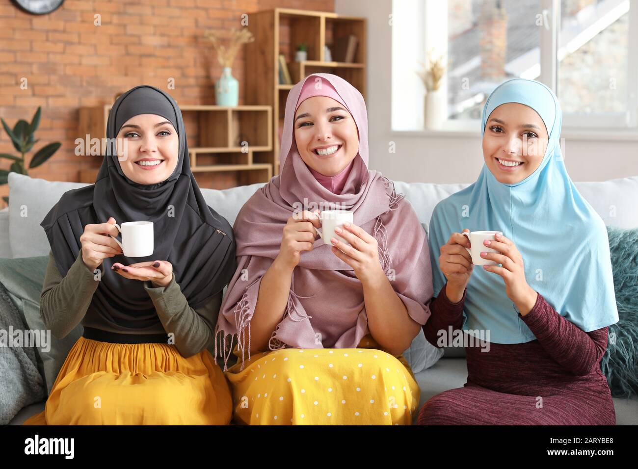Beautiful young Muslim women drinking tea at home Stock Photo - Alamy