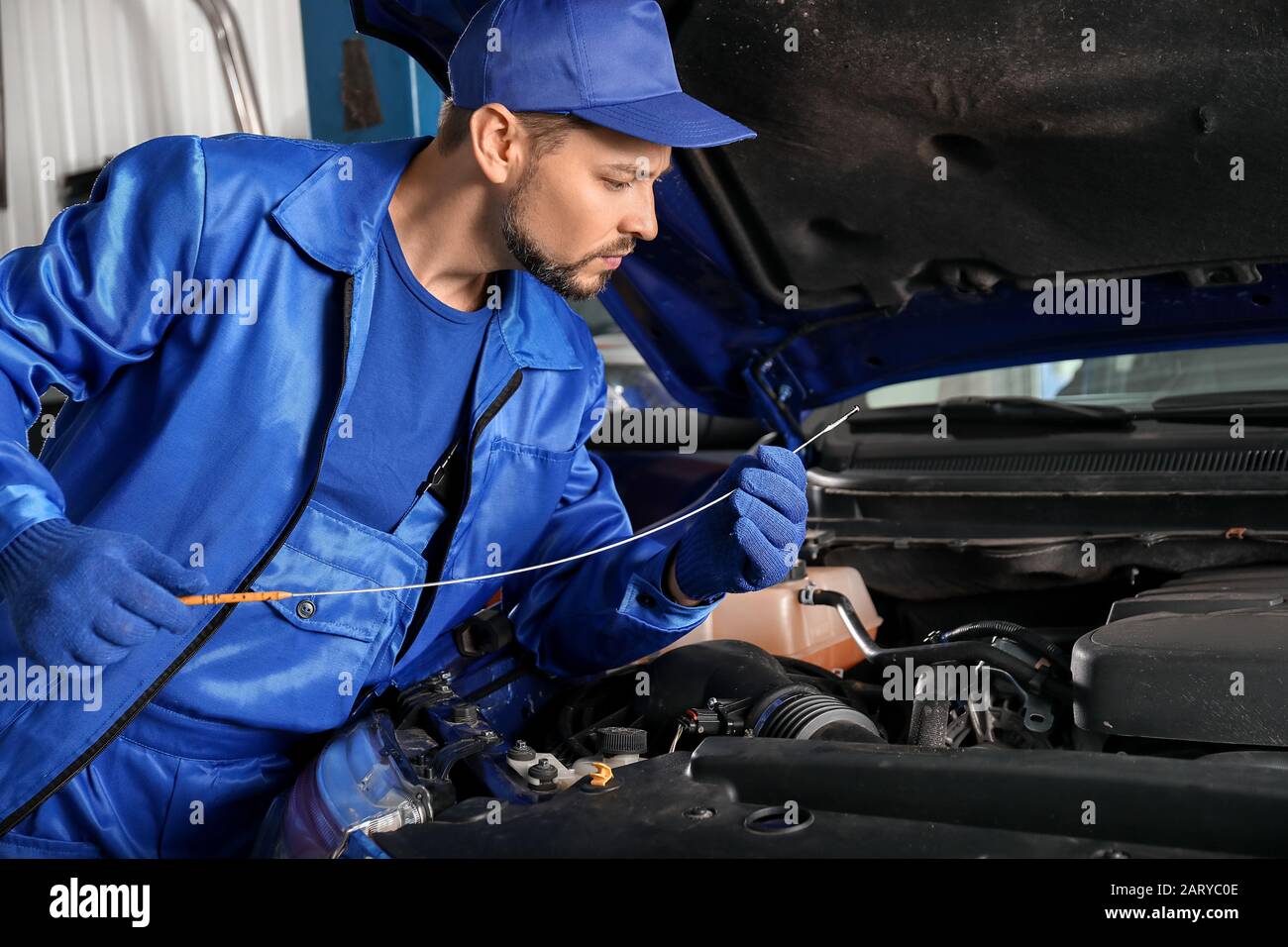 Male mechanic checking level of oil in car engine Stock Photo - Alamy